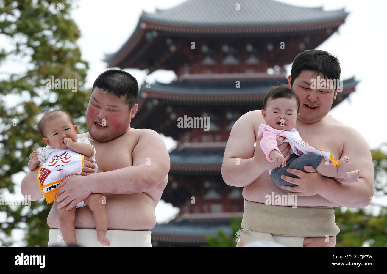 Held by college students sumo wresters, a couple of babies cry in their ...
