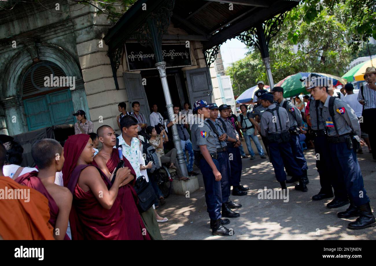 Police officers stand guard as monks, left, supporters of Ye Min Oo ...
