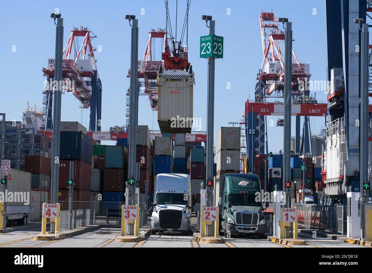 A large crane lifts shipping containers onto trucks at the Long Beach ...