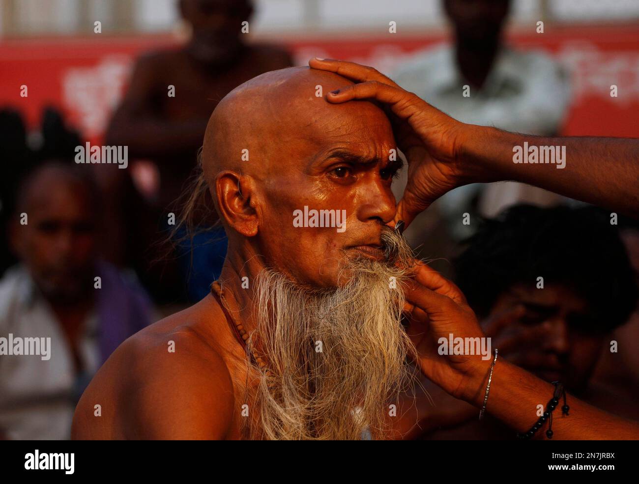 An Indian Hindu man gets tonsured on the banks of the Ganges River, in ...