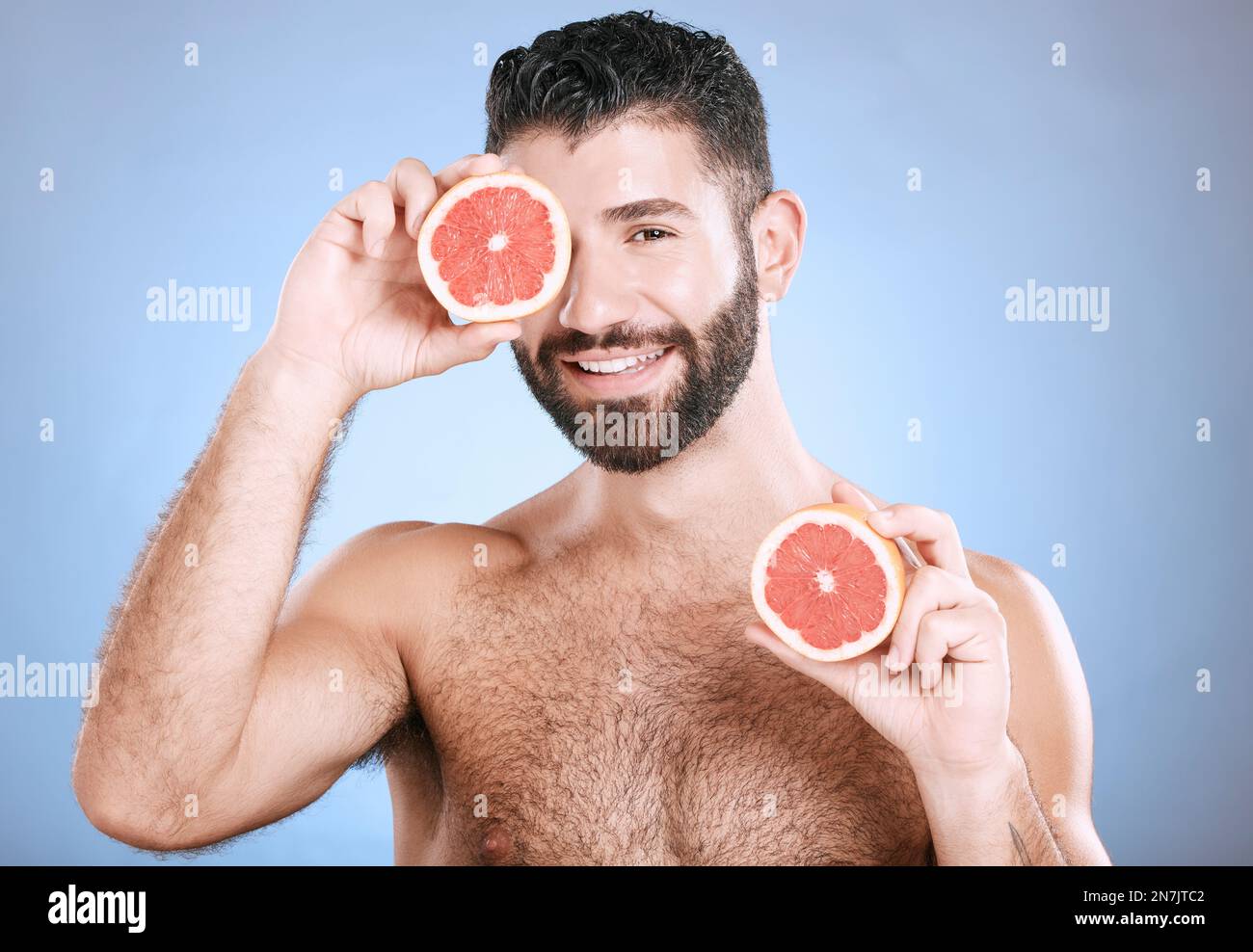 Portrait, beauty and grapefruit with a man model in studio on a blue ...