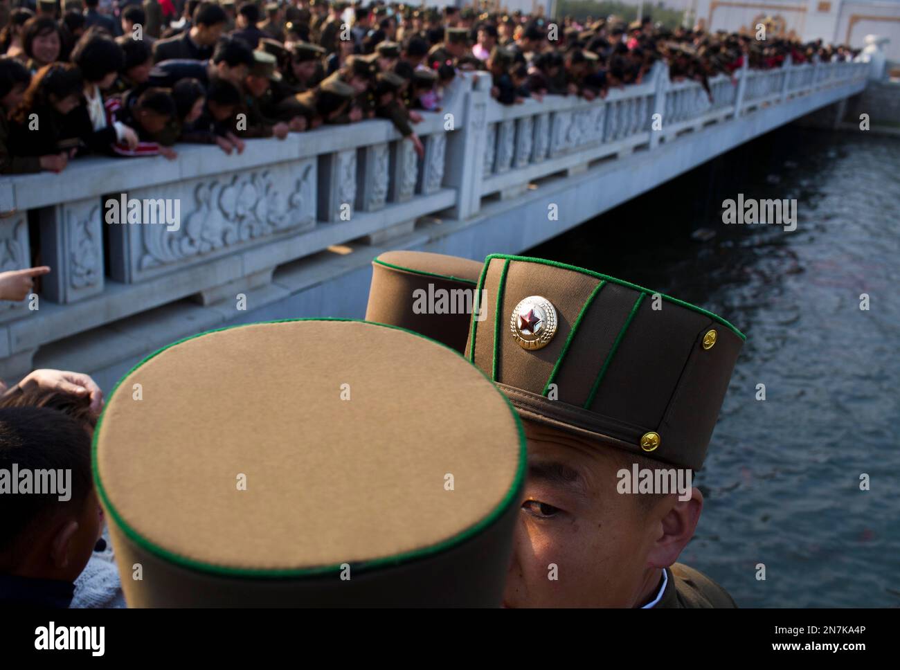 North Korean soldiers and civilians stand on a foot bridge to look at ...