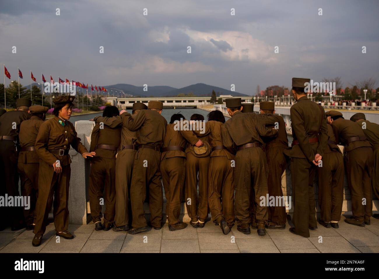 North Korean soldiers and civilians stand on a foot bridge to look at ...