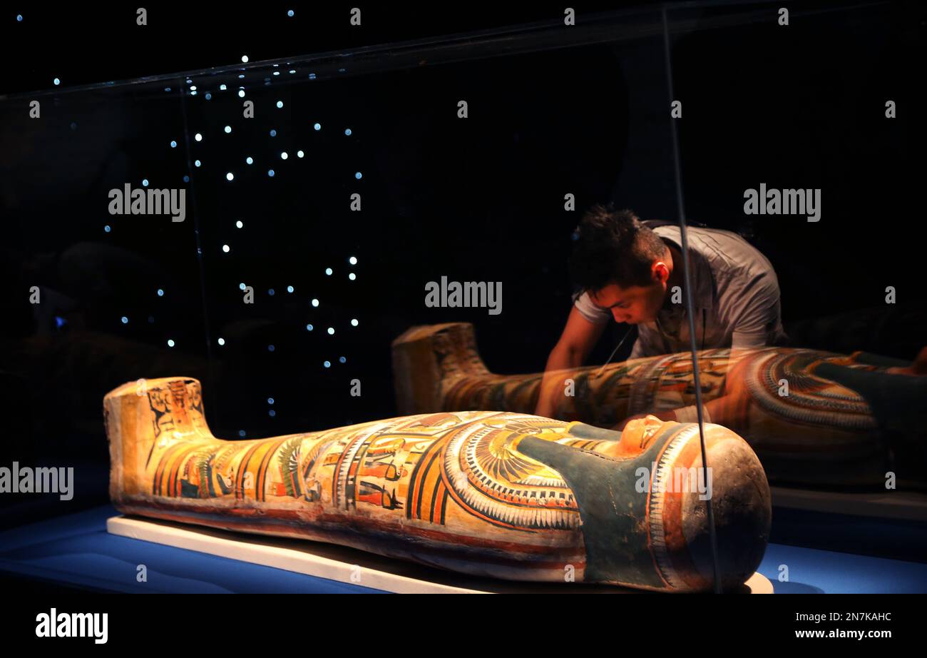 A man examines the cartonnage case for the Mummy of Nesperennub, an ...