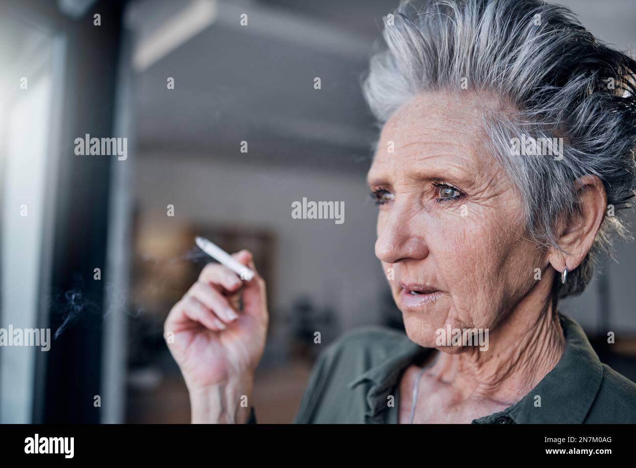 Thinking Nicotine And A Senior Woman Smoking A Cigarette In Her Home While Looking Out From A