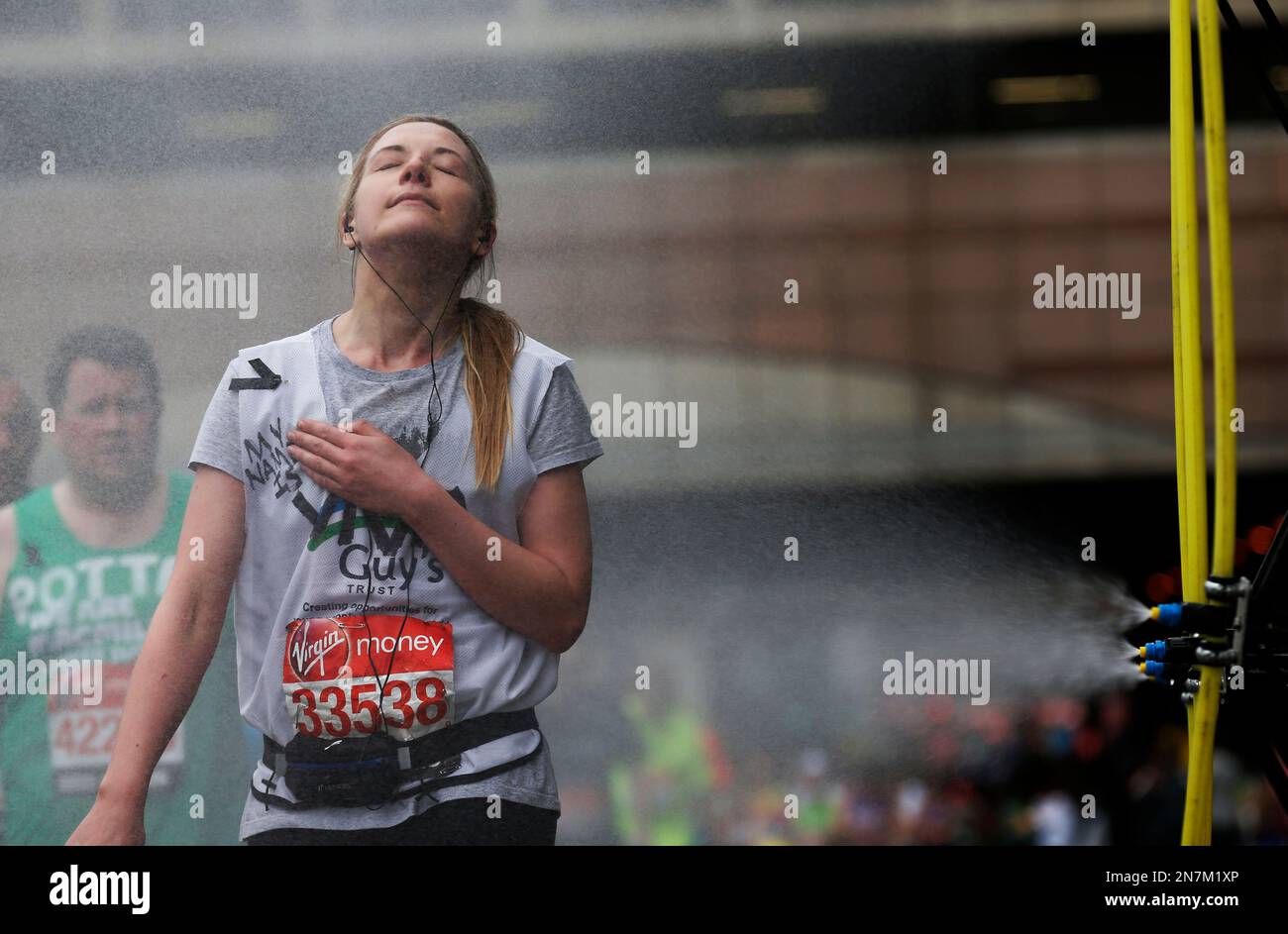 A runner cools down running through water sprays on the route during ...