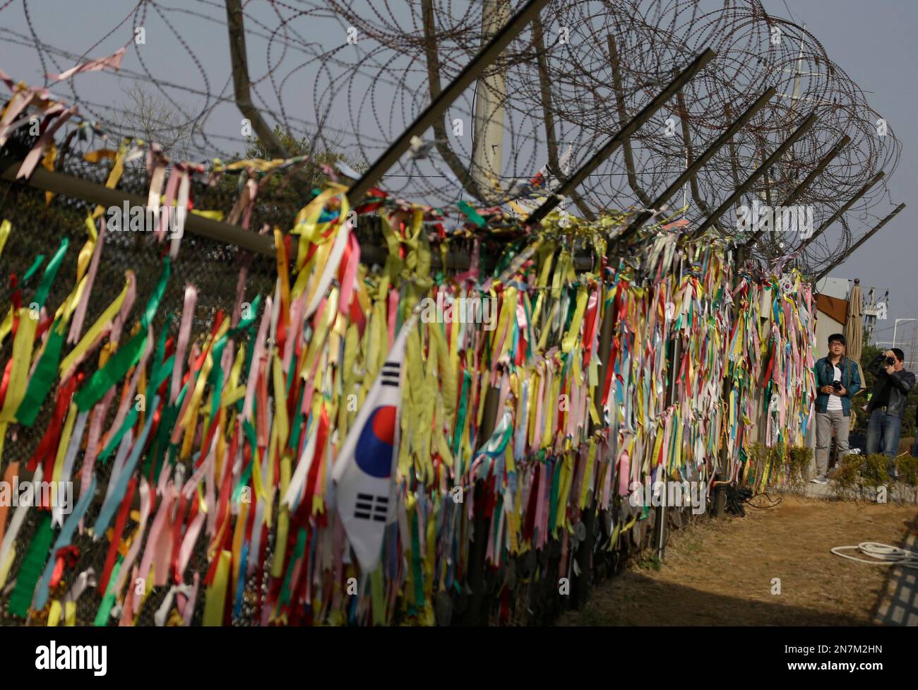 Visitors take souvenir photos near the military wire fences hanging ...