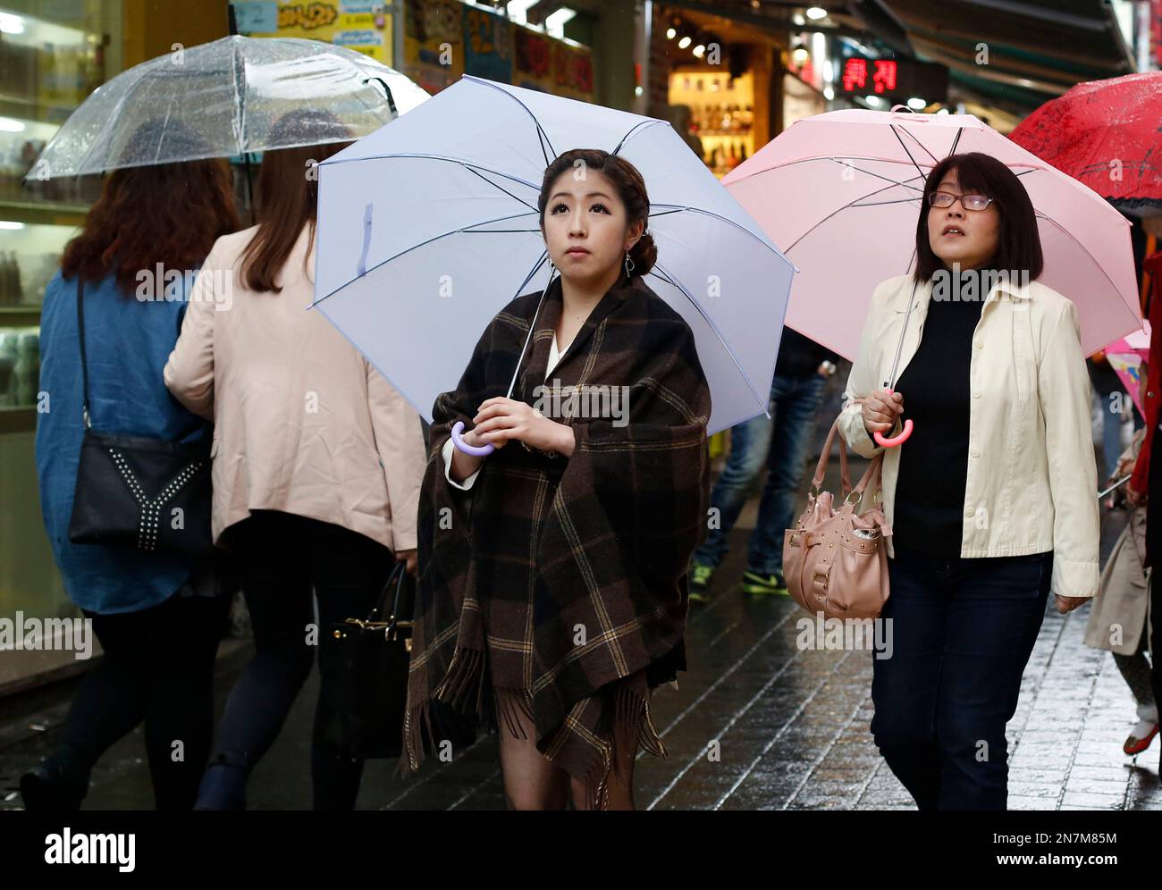 Shoppers walk on the shopping district under the rain in Seoul, South ...