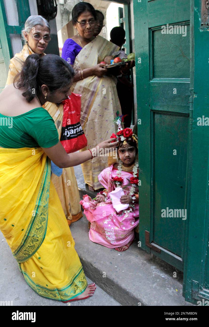 A Hindu devotee decorates a young girl with flowers before being ...