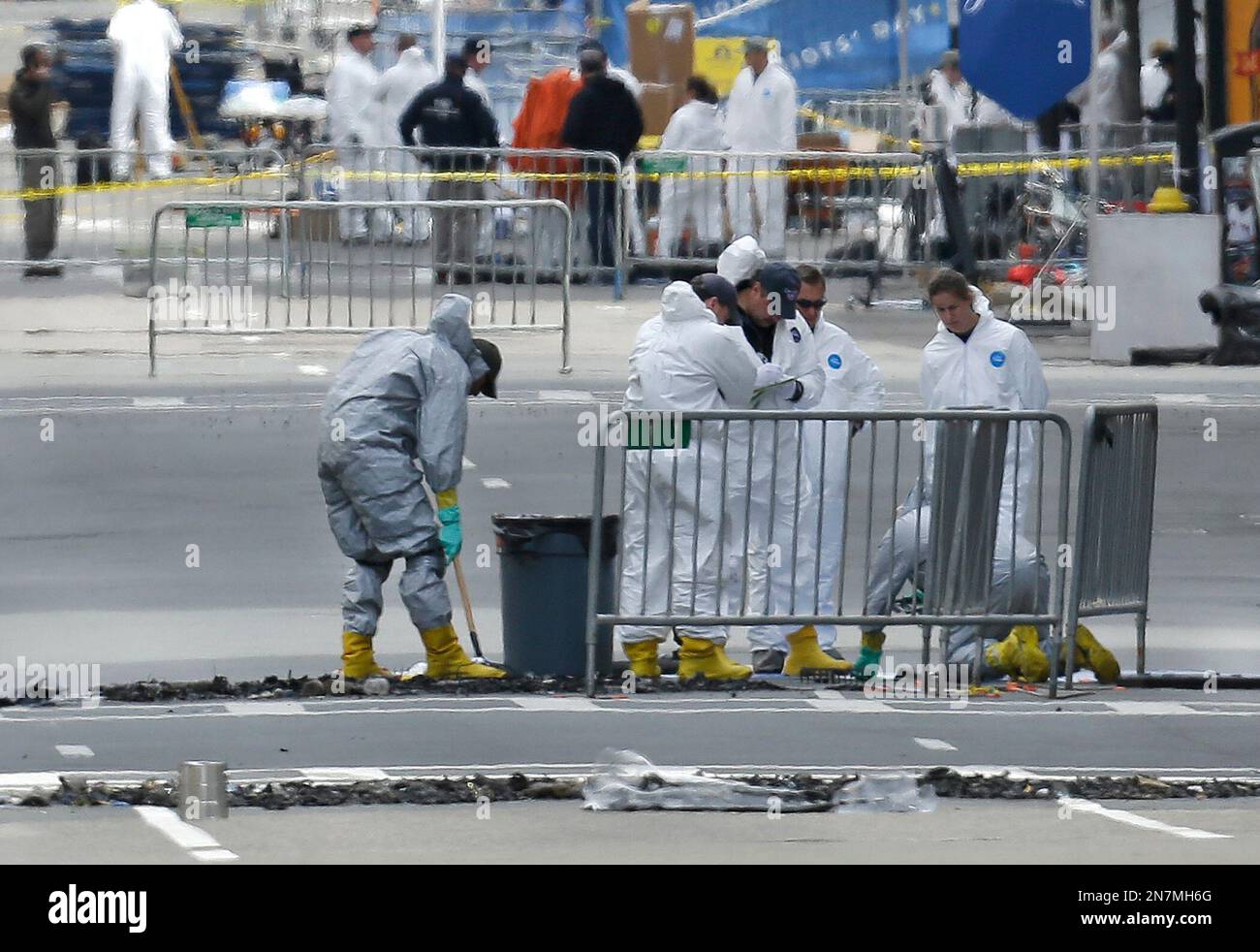 People in protective suits rake and examine material on Boylston Street ...