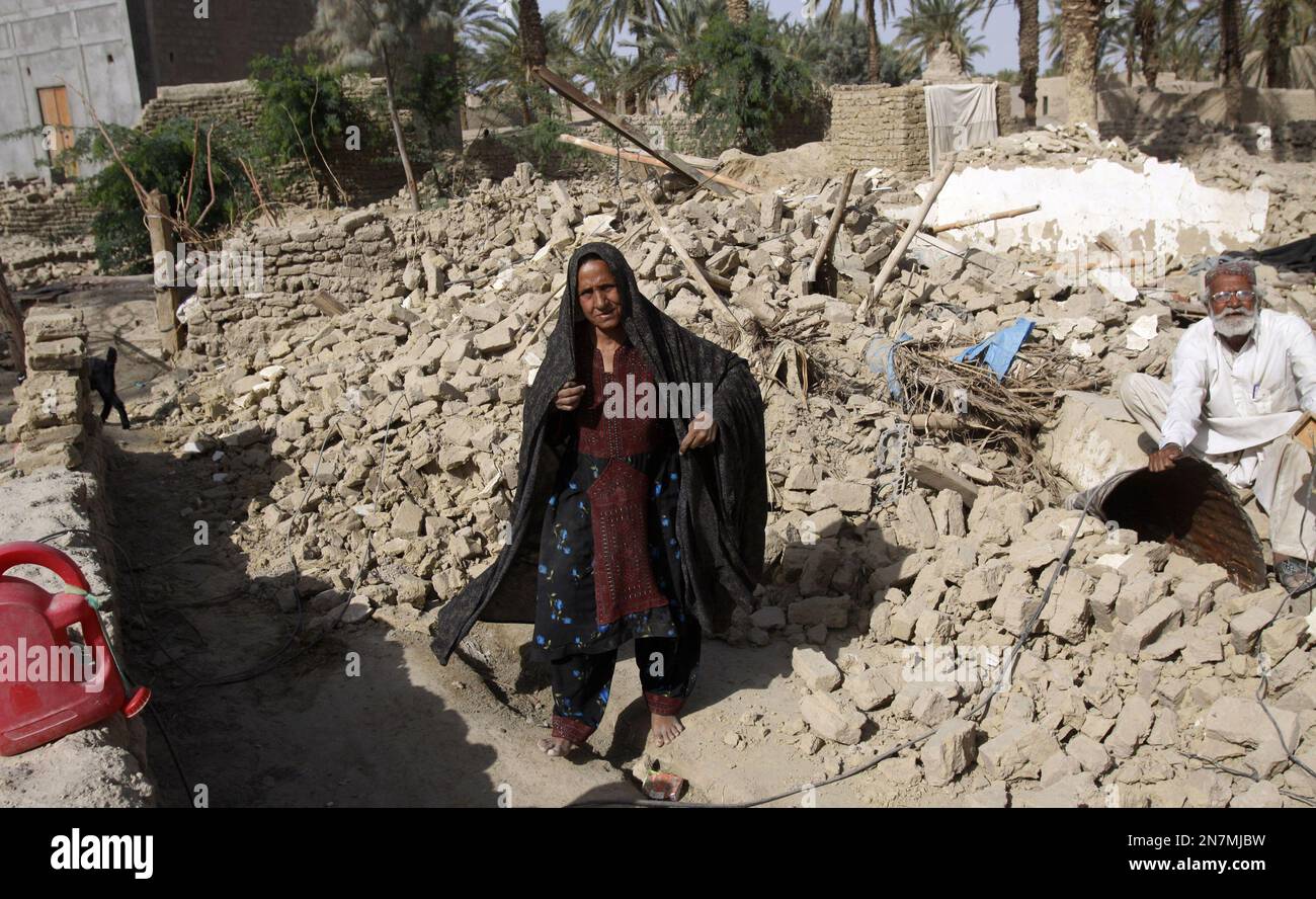 Pakistani villagers pause while collecting their belongings from a ...