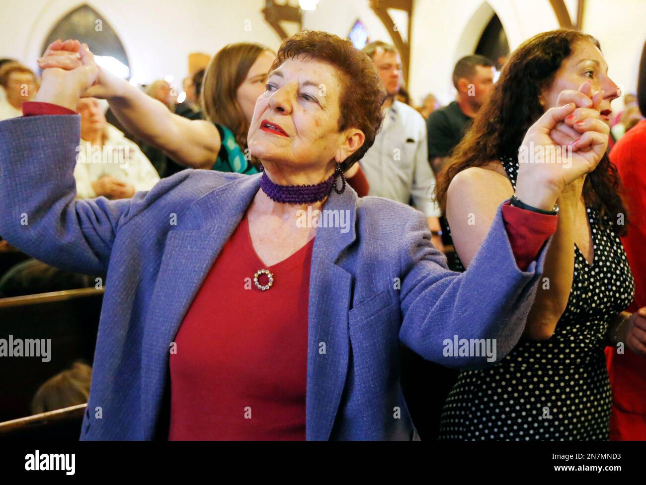 Rita Ferullo, center, holds hands with other worshipers during a ...