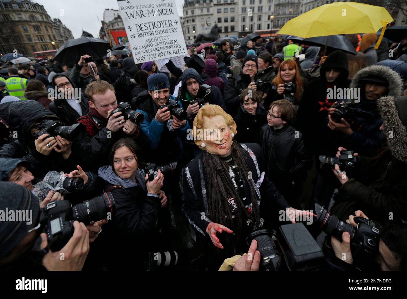 Photographer gather around a protester wearing a mask depicting former ...