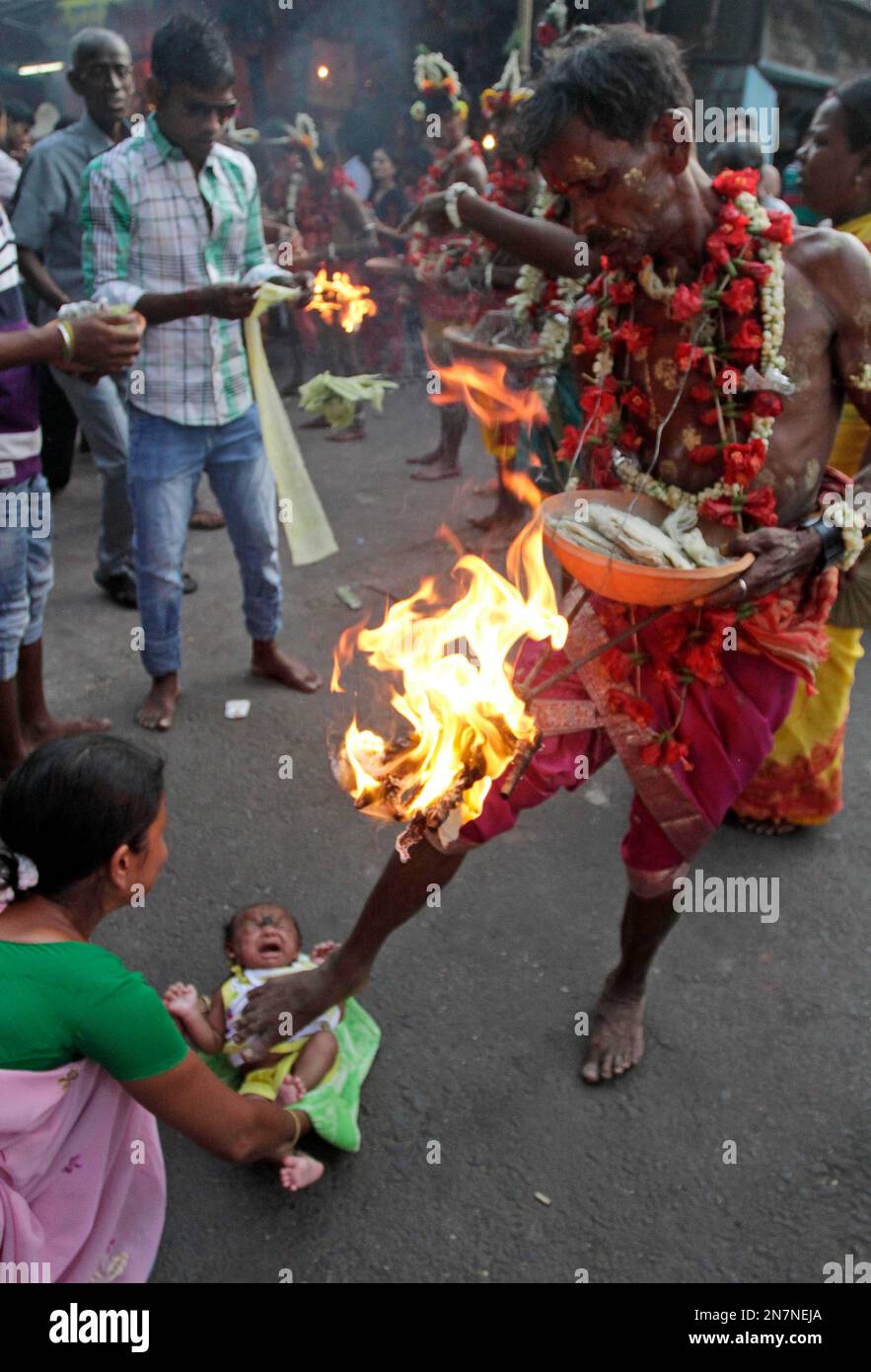 A Hindu devotee touches a baby with his feet as an act of blessing ...