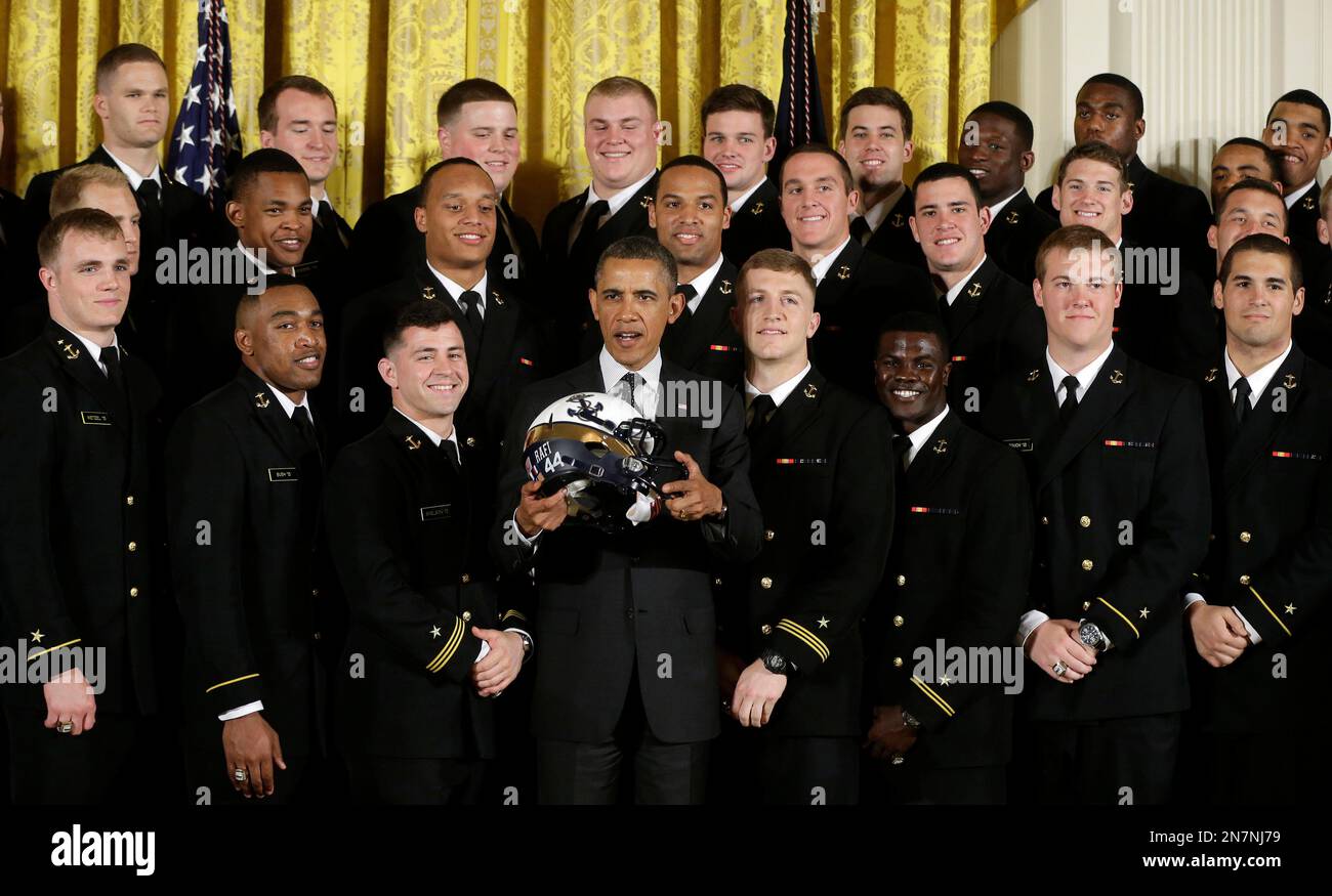 President Barack Obama holds a football helmet as he poses for a ...