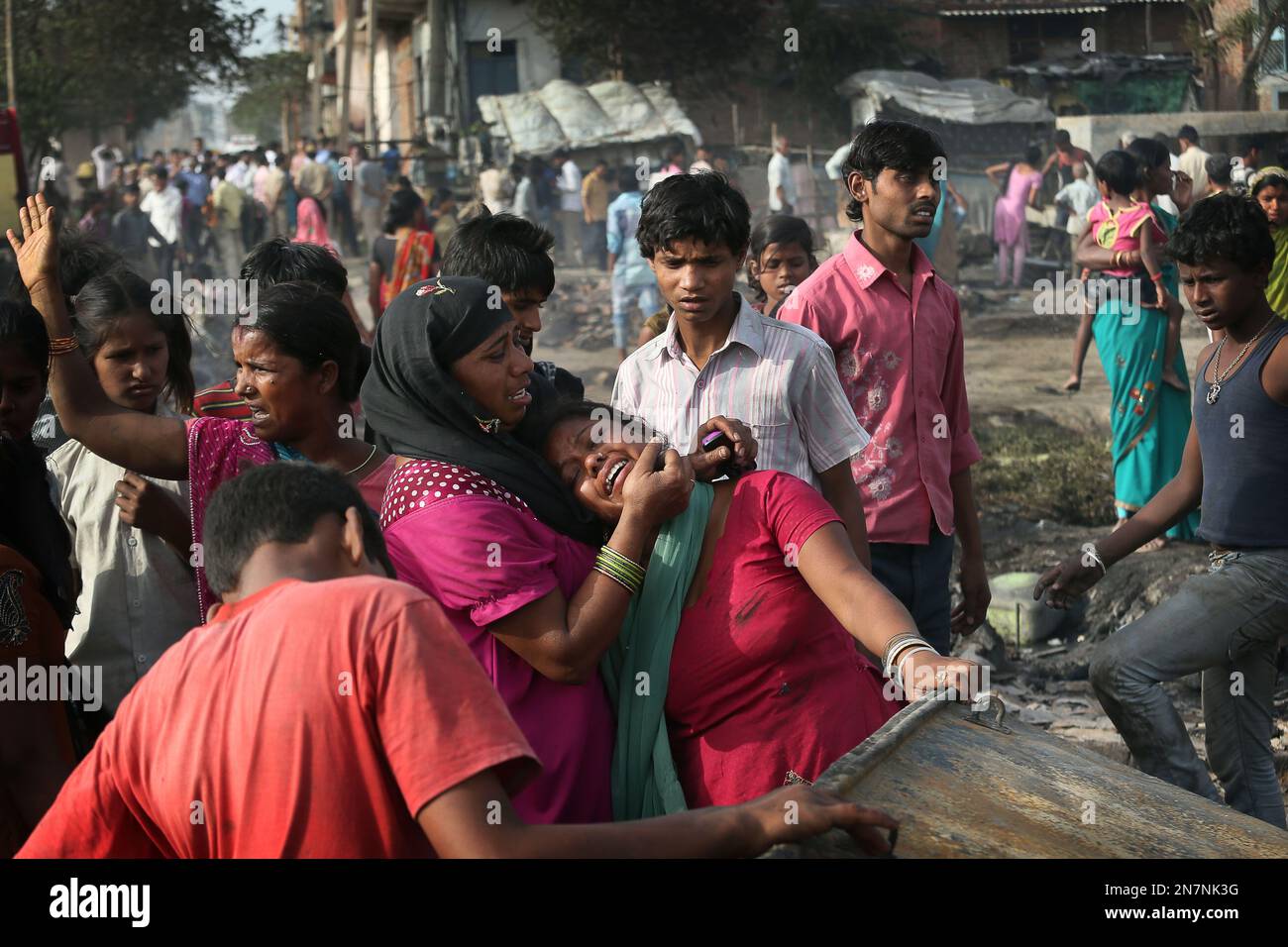 An Indian woman cries as she is consoled by another after a fire gutted ...