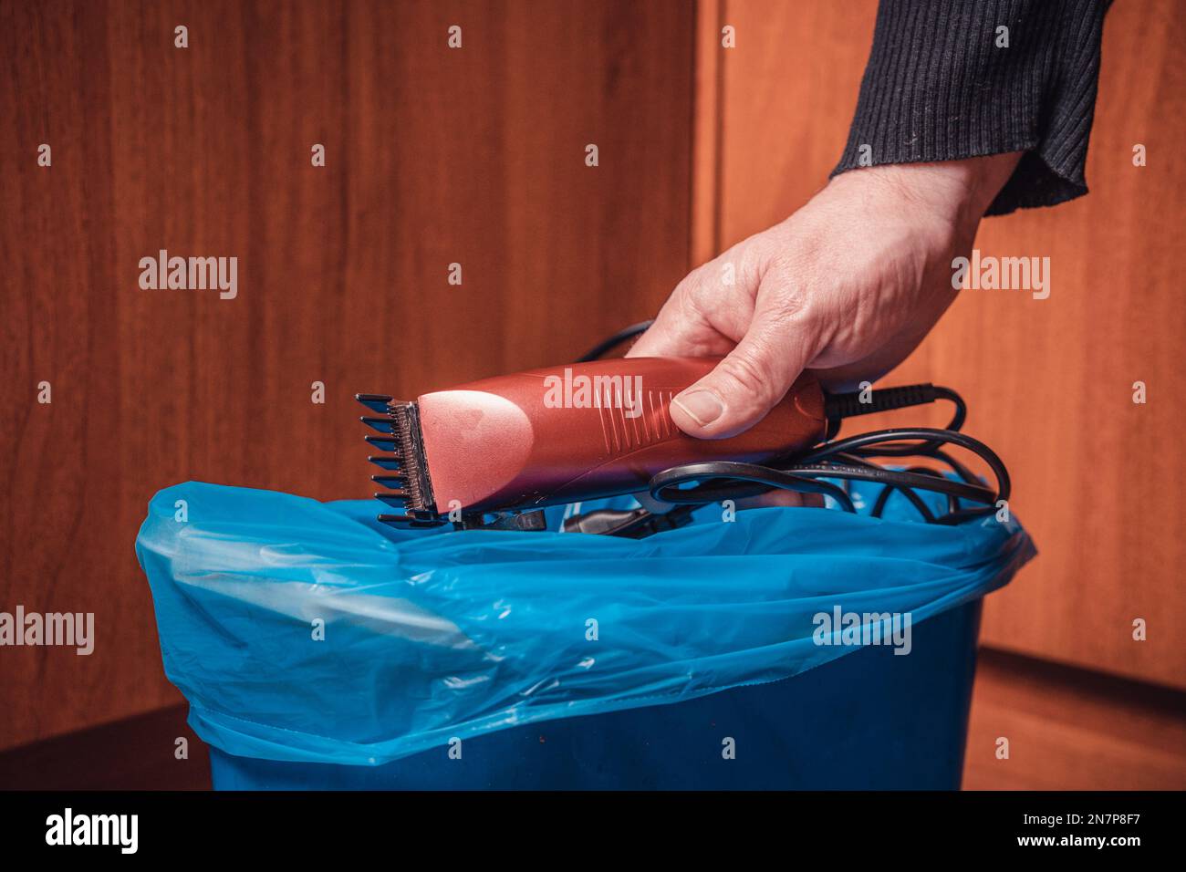 The man throws the clipper into the trash can. Man's hand with a ...