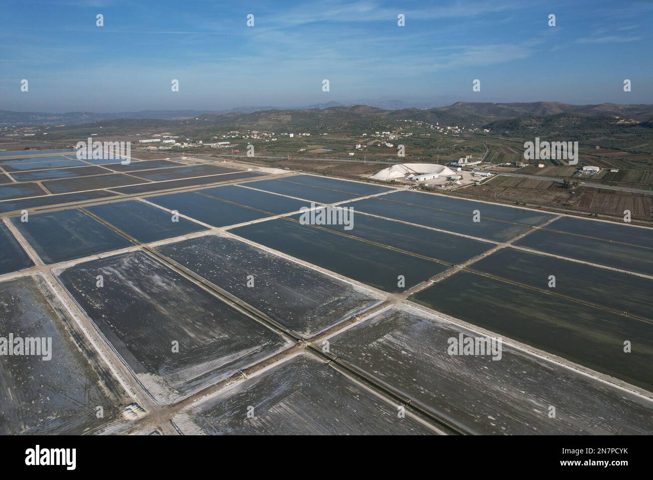 A bird's eye view of saline fields in Albania under a cloudy blue sky ...