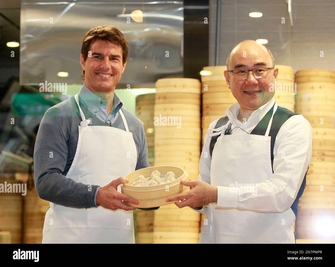 Seen through glass, actor Tom Cruise, left, displays his dumplings at ...
