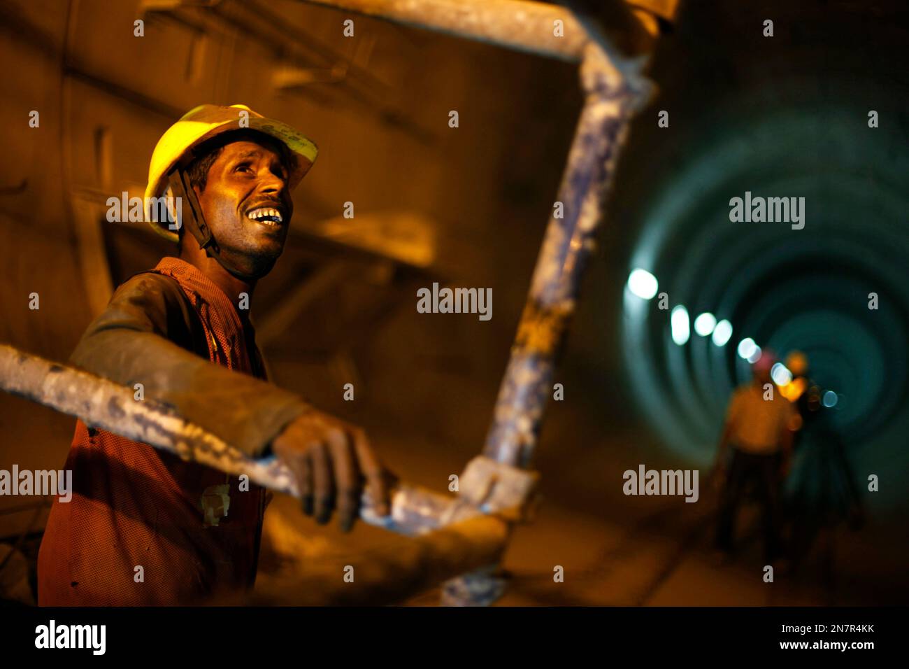 An Indian laborer talks to his colleague as they install lights inside ...