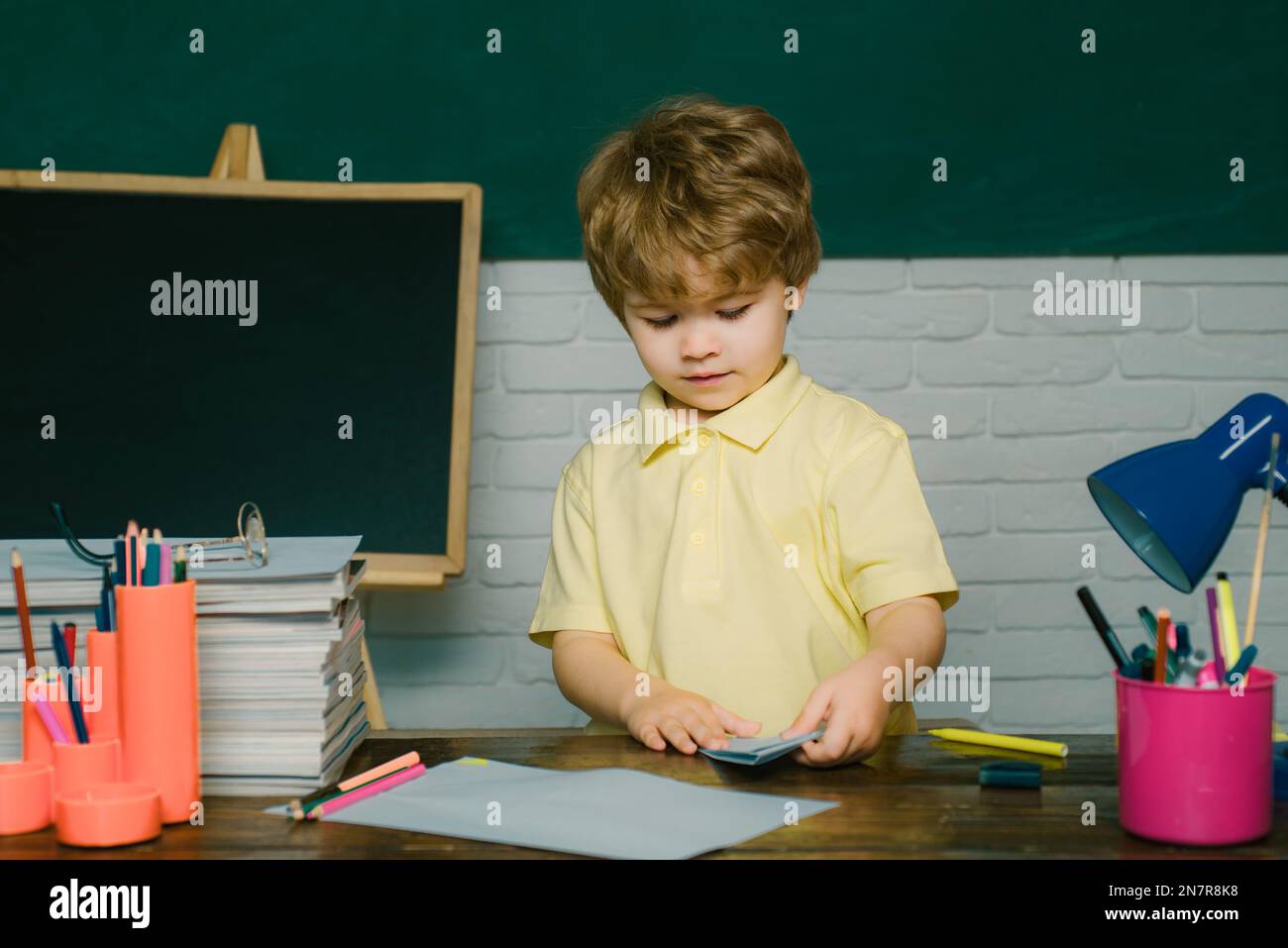 Kid is learning in class on background of blackboard. Kids gets ready ...