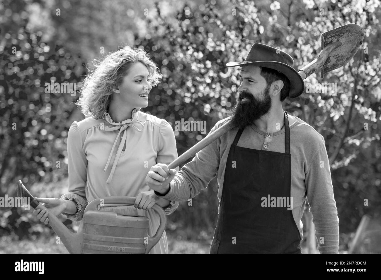 Portrait of a young happy couple in yard during spring season. Farming ...