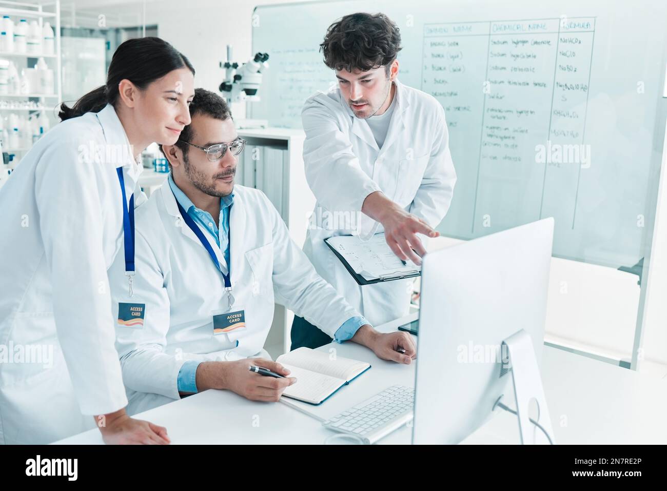 Modifying their theory. a group of scientists working together on a computer in a lab Stock ...