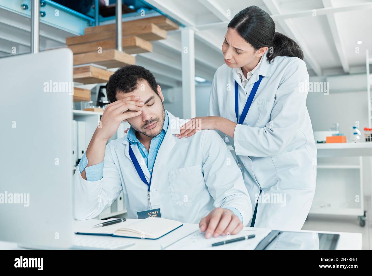 Dont beat yourself up about it. a young scientist looking stressed out while being consoled by a ...