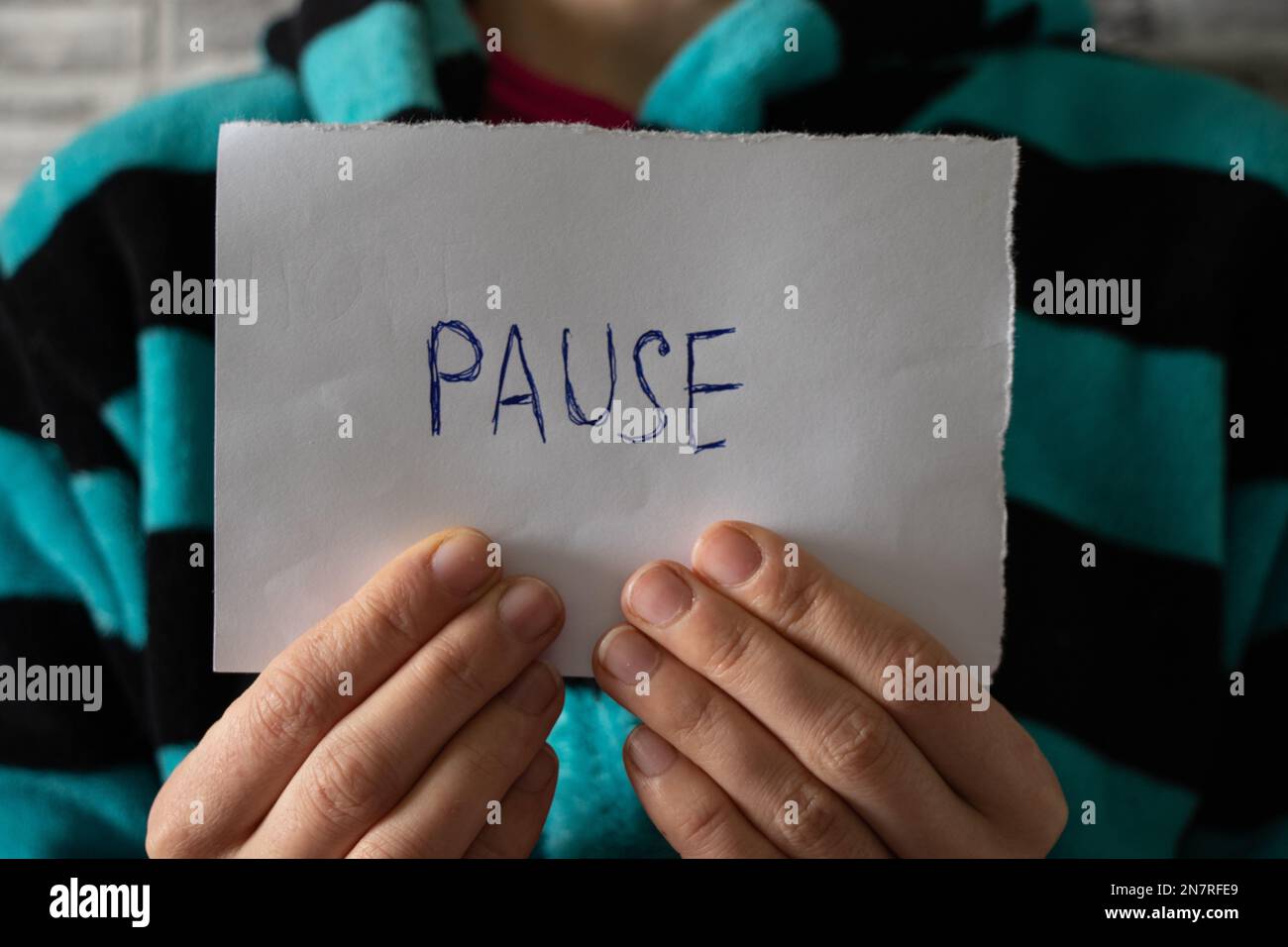 word pause is written on a piece of paper that the quarantined girl is ...