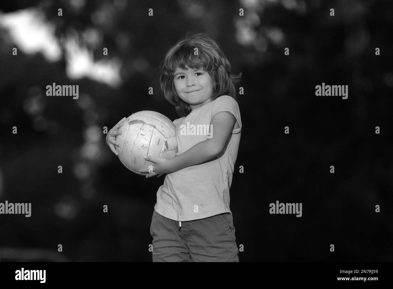 Excited child boy kicking ball in the grass outdoors. Soccer kids ...