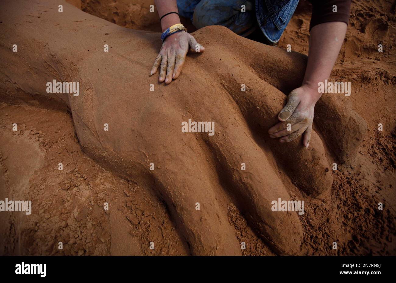 An artist shapes a hand on a sand sculpture that depicts Jesus Christ ...