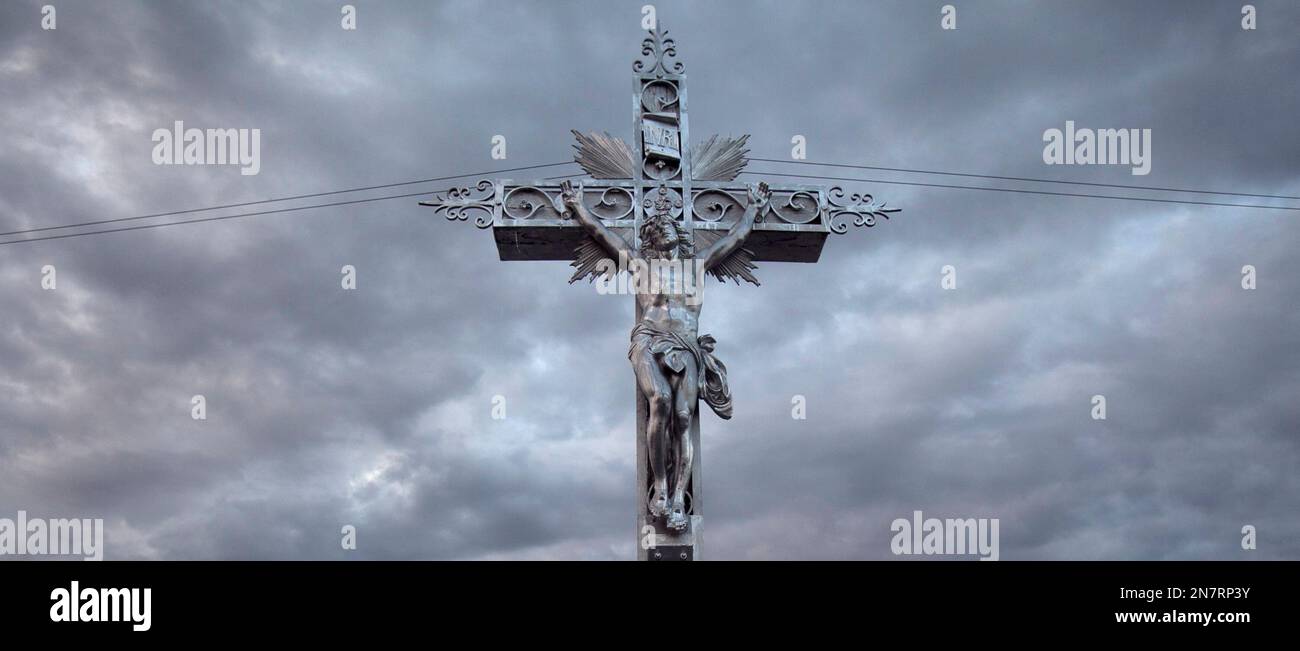 The crucifix of Calvaire Miracle Mount is backdropped by a cloudy sky ...