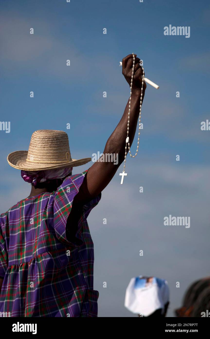 A woman chants prayers as she holds up her rosary during a pilgrimage ...