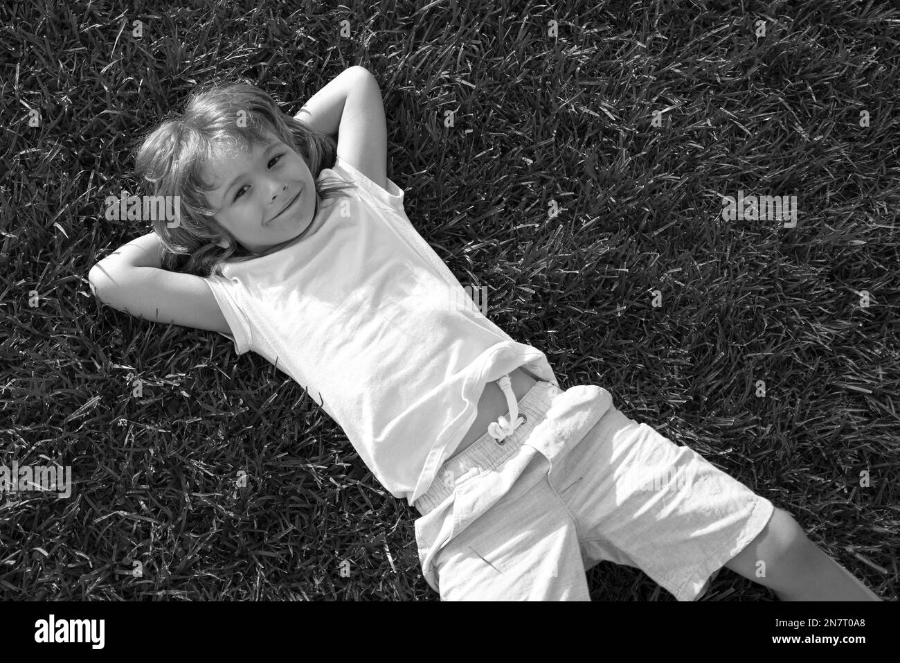 Happy child lying on grass background. Cute kid child boy enjoying on ...