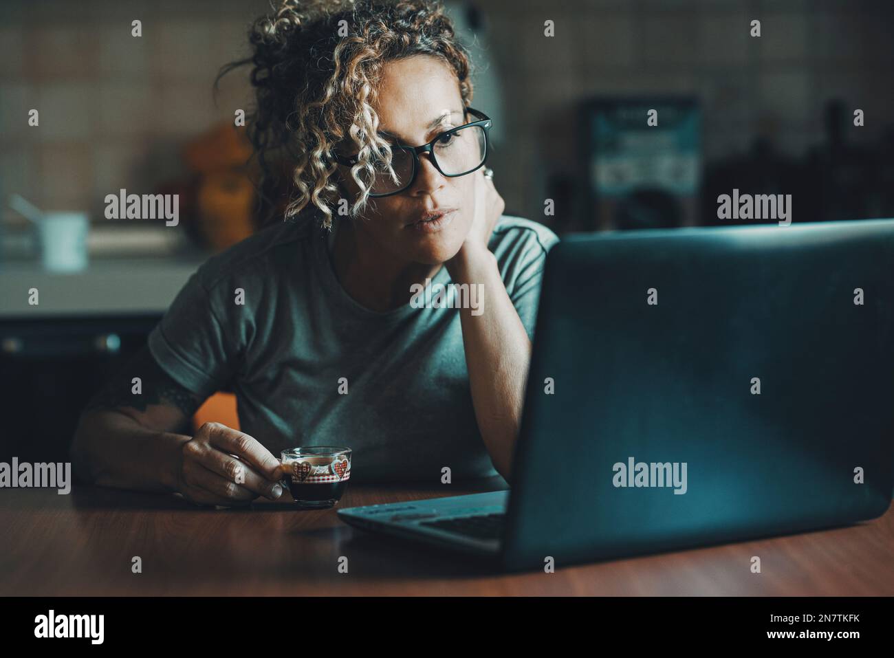 One adult woman using computer in early morning at home drinking an ...