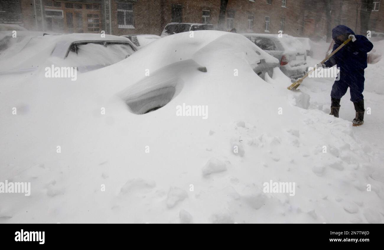 A driver shovels snow off his vehicle in Kiev, Ukraine, Saturday, March ...