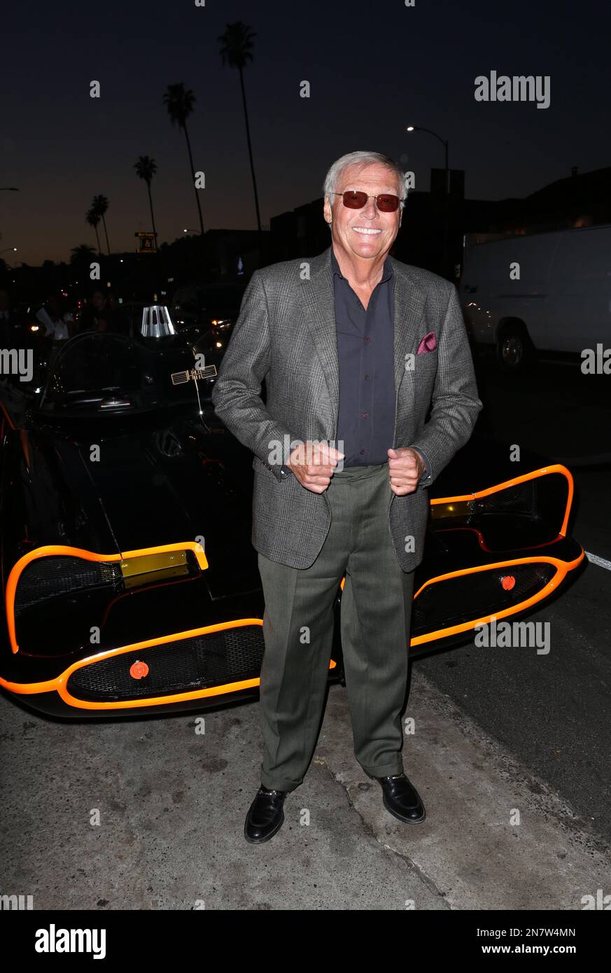 Adam West poses in front of the original Batmobile at the launch event ...
