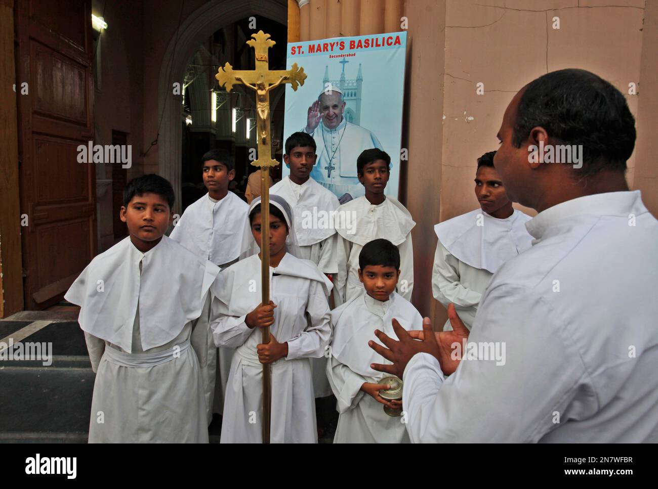 An Indian catholic priest gives instructions to altar boys and girls as ...