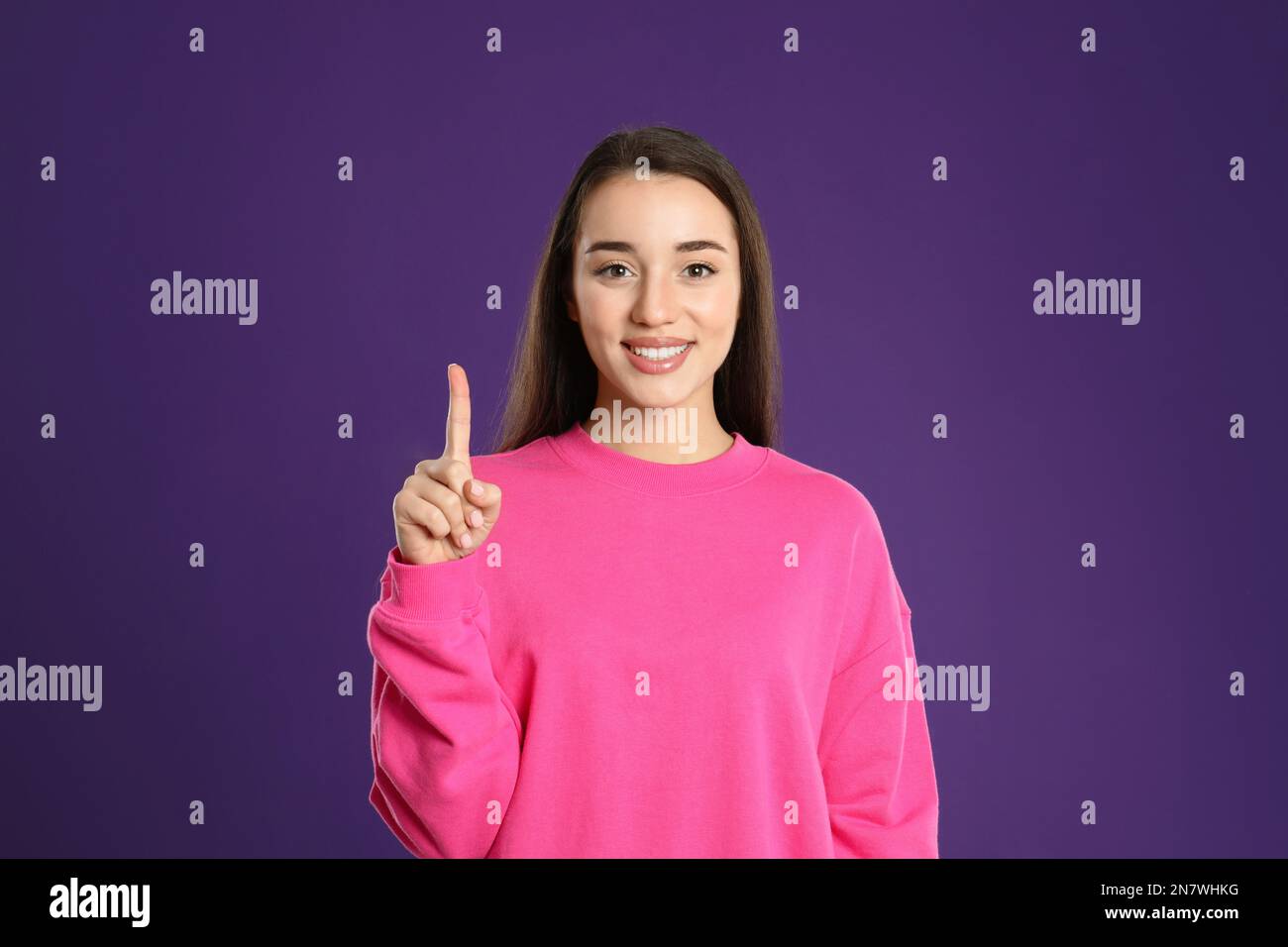 Woman showing number one with her hand on purple background Stock Photo ...