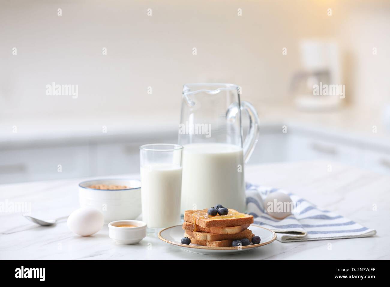 Toasted bread with jam and blueberries on white marble table in kitchen ...