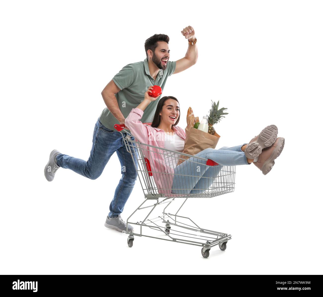 Young man giving his girlfriend ride in shopping cart with groceries on ...