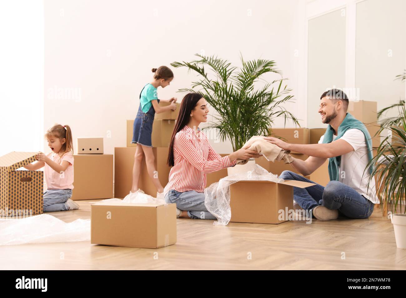 Happy family unpacking moving boxes in new house Stock Photo - Alamy