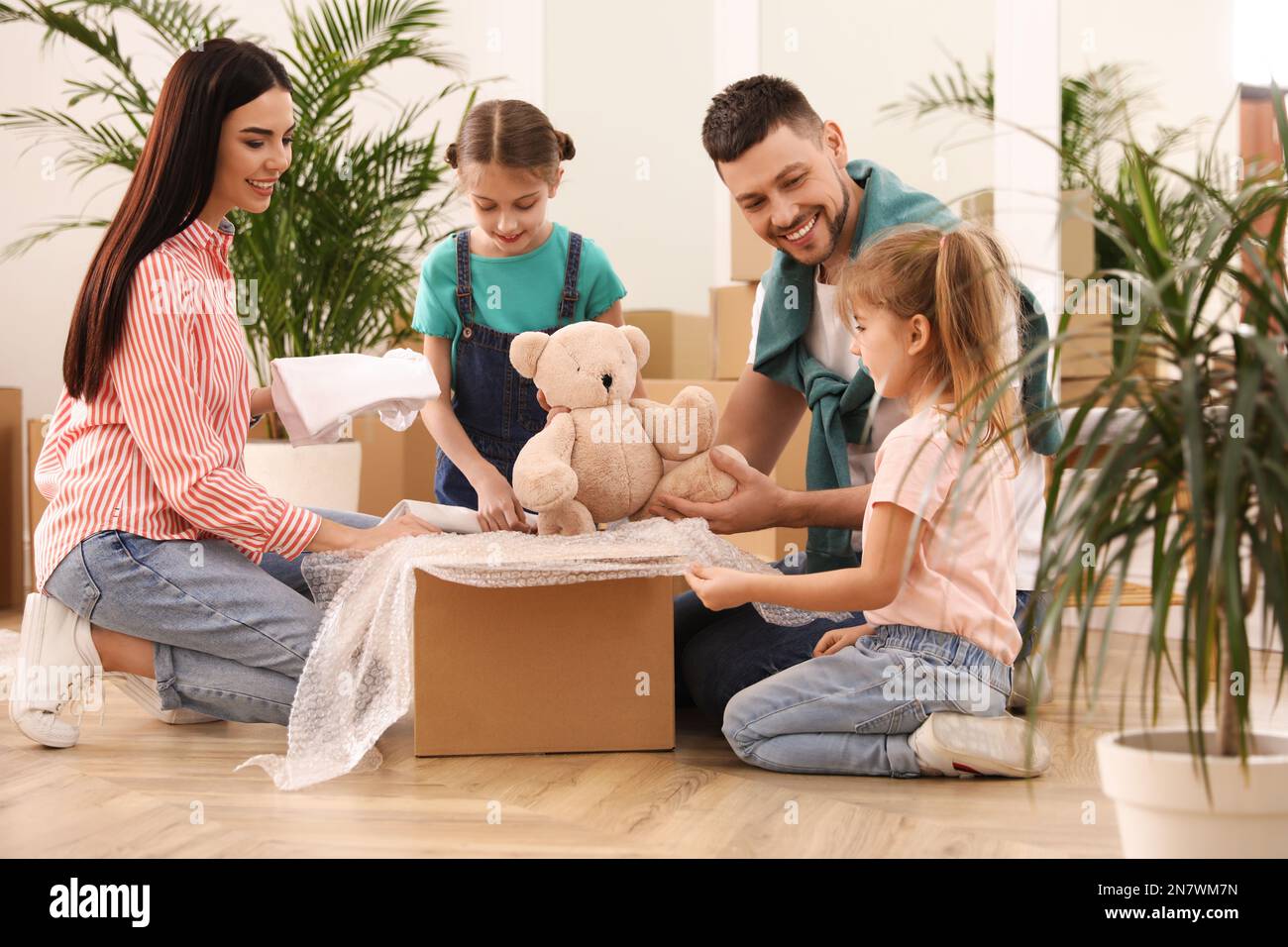 Happy family unpacking moving box in new house Stock Photo - Alamy