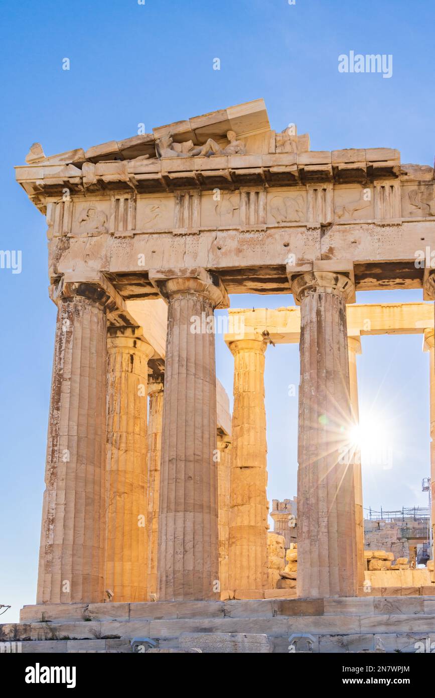 Sun hiding behind the columns of the Parthenon temple at Acropolis site on a sunny evening in ...