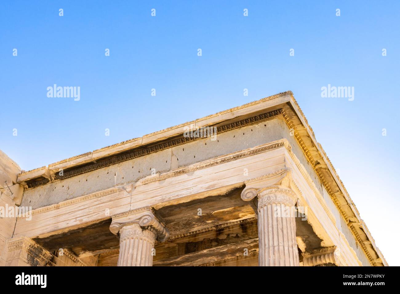 Sun hiding behind the columns of the Parthenon temple at Acropolis site on a sunny evening in ...
