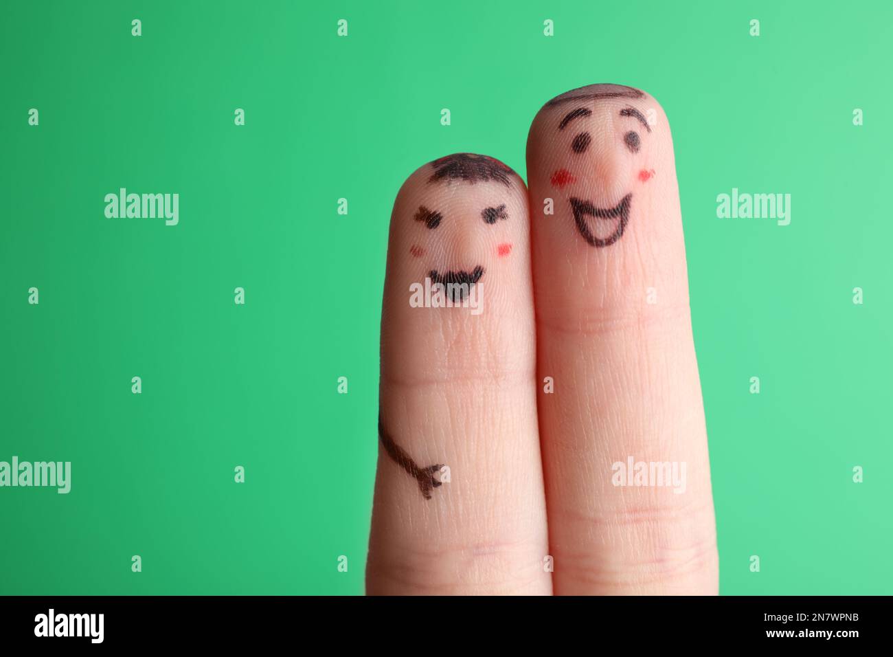 Two fingers with drawings of happy faces on green background. Spending ...