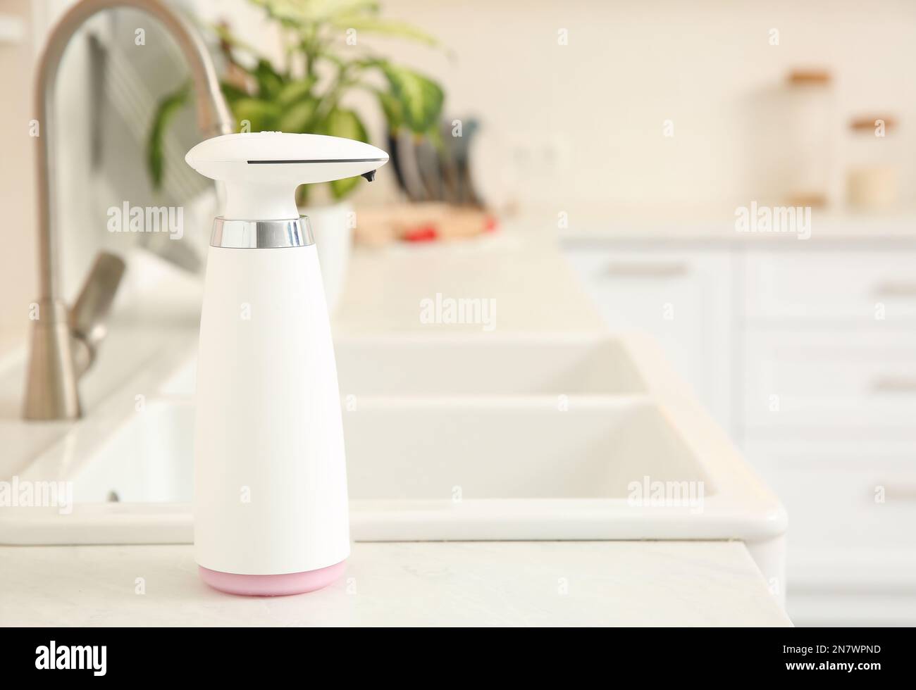 Modern automatic soap dispenser on countertop in kitchen. Space for ...