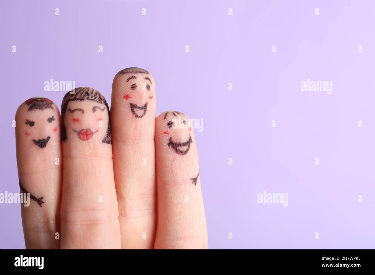 Four fingers with drawings of happy faces on violet background, space ...
