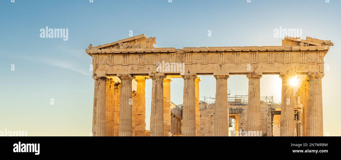 Sun hiding behind the columns of the Parthenon temple at Acropolis site on a sunny evening in ...