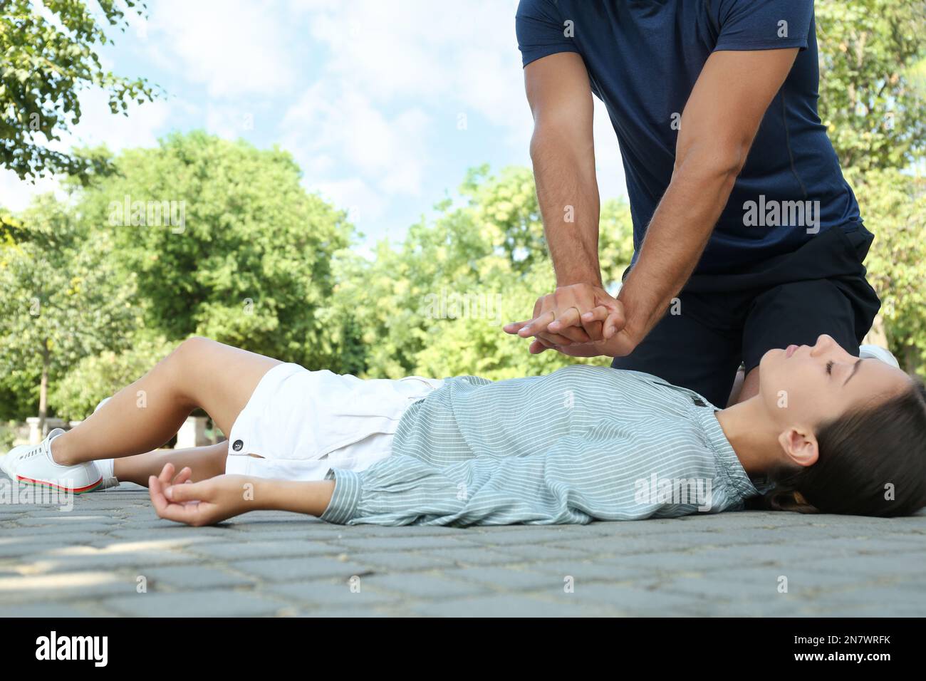 Man performing CPR on unconscious young woman outdoors. First aid Stock ...
